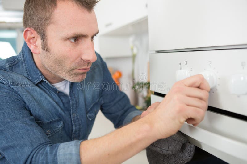 Man turning dial on oven stock photo. Image of housework - 335182758