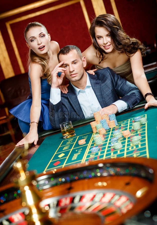 Man with Two Girls Playing Roulette at the Gambling House Stock Photo ...