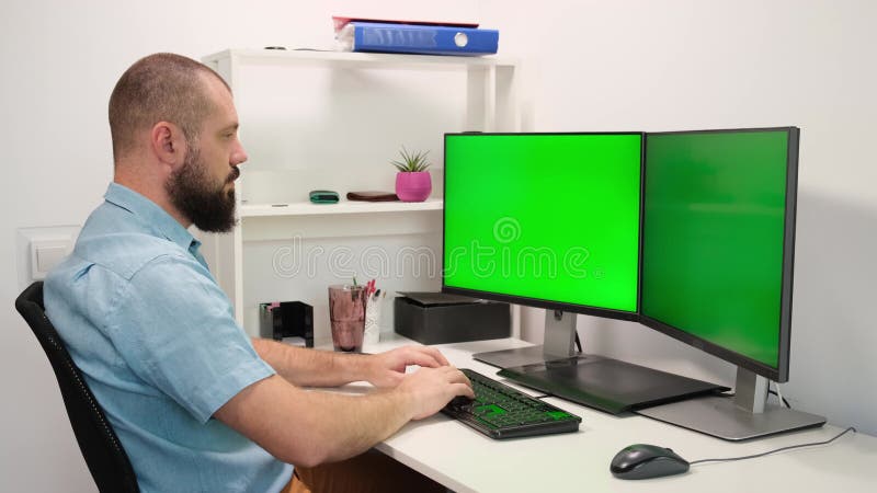 Man Type on the Keyboard on Two Monitors with the Green Screen. Stock ...