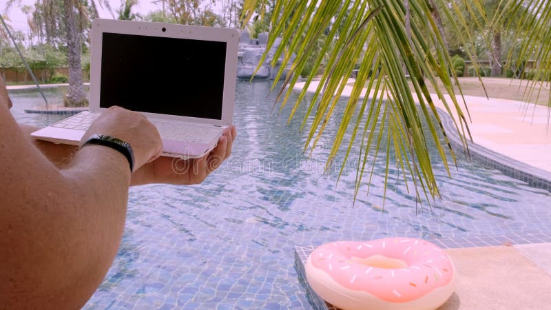 A Man is Typing on His Laptop while Sitting by the Pool. Mens Hands on ...