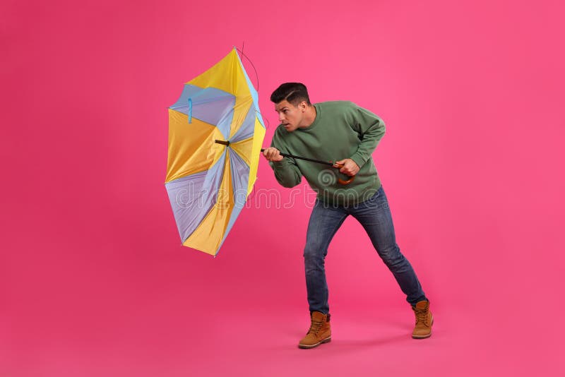 Man with Umbrella Caught in Gust of Wind on Pink Background Stock Photo ...