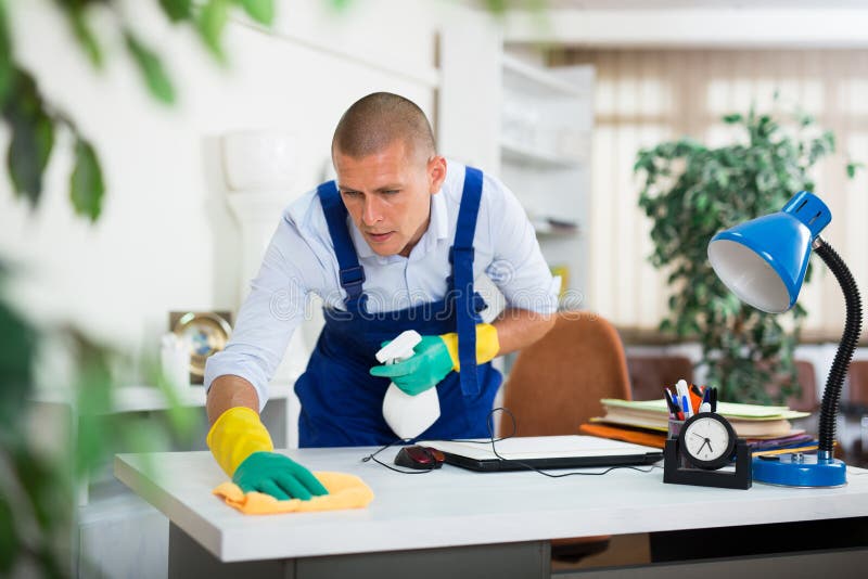 Man in Uniform is Cleaning Dust from the Desk in Office Stock Photo ...