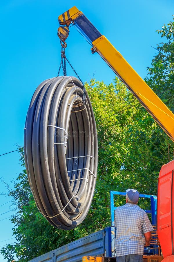 Man Unloads a Plastic Pipe Rolled into a Circle for a Water Pipe Using ...