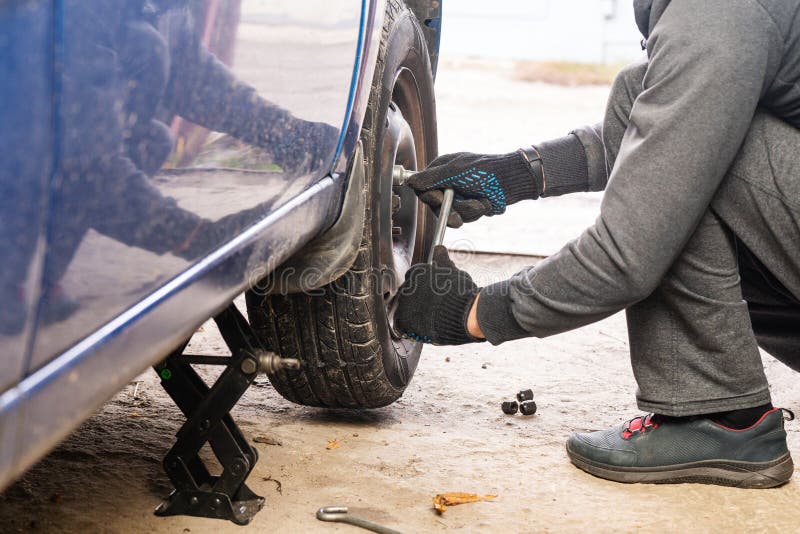 A Man Unscrews a Car Wheel in a Garage. Replacing Car Wheels Stock ...