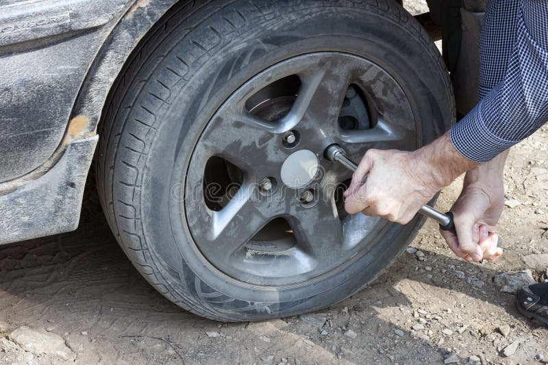 A Man Unscrews a Flat Car Tire Outdoors. Wheel Replacement Stock Image ...