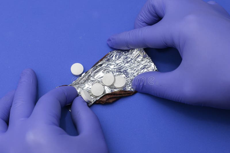A Man Unwraps a Candy Wrapper in Which Pills are Wrapped on a Blue ...