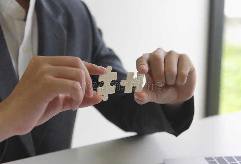 A Man Uses Both Hands To Try To Connect the Two Jigsaw Puzzles Together ...