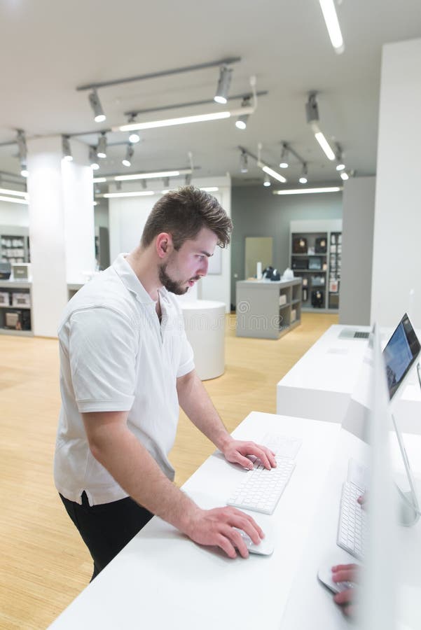 Man Uses a Computer in a Modern Electronics Store. Buyer Selects a ...