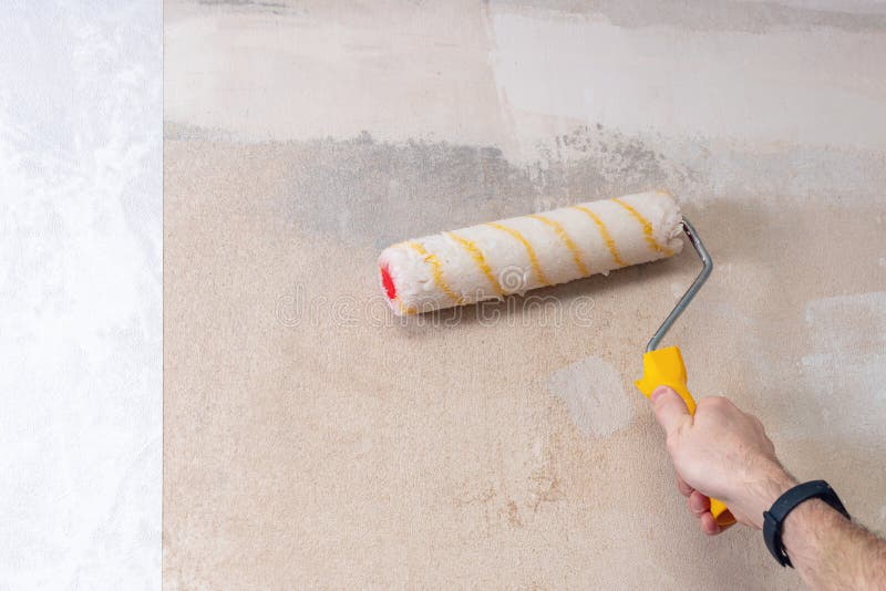 A Man Uses a Roller To Apply Glue To a Wall To Paste Wallpaper. Room ...