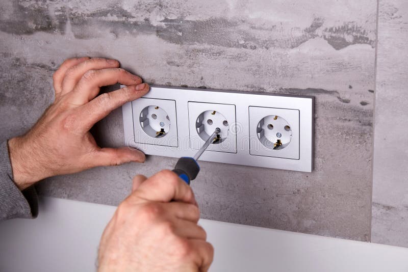 A Man Uses a Screwdriver To Install an Electrical Outlet on a Porcelain ...