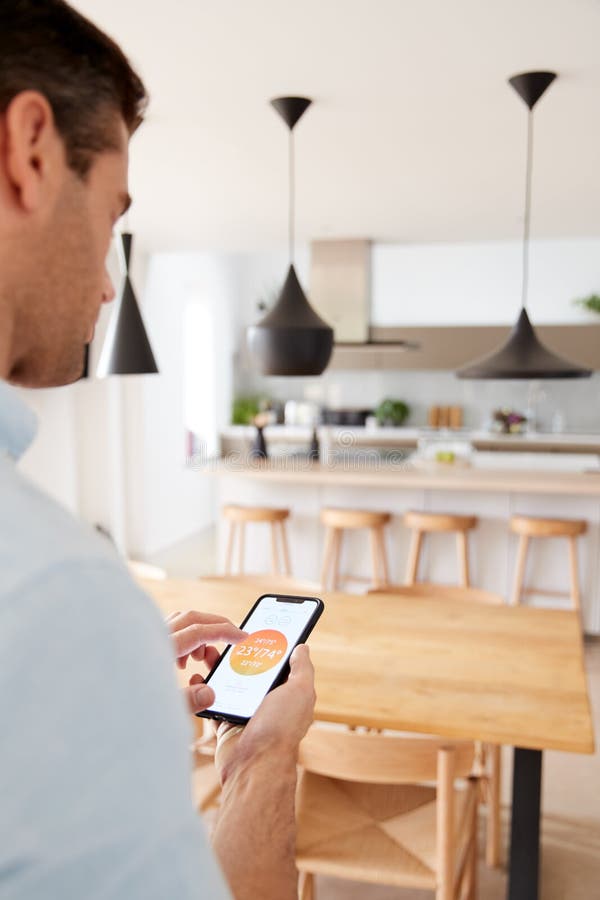 Man Using App on Smart Phone To Control Central Heating Temperature in ...
