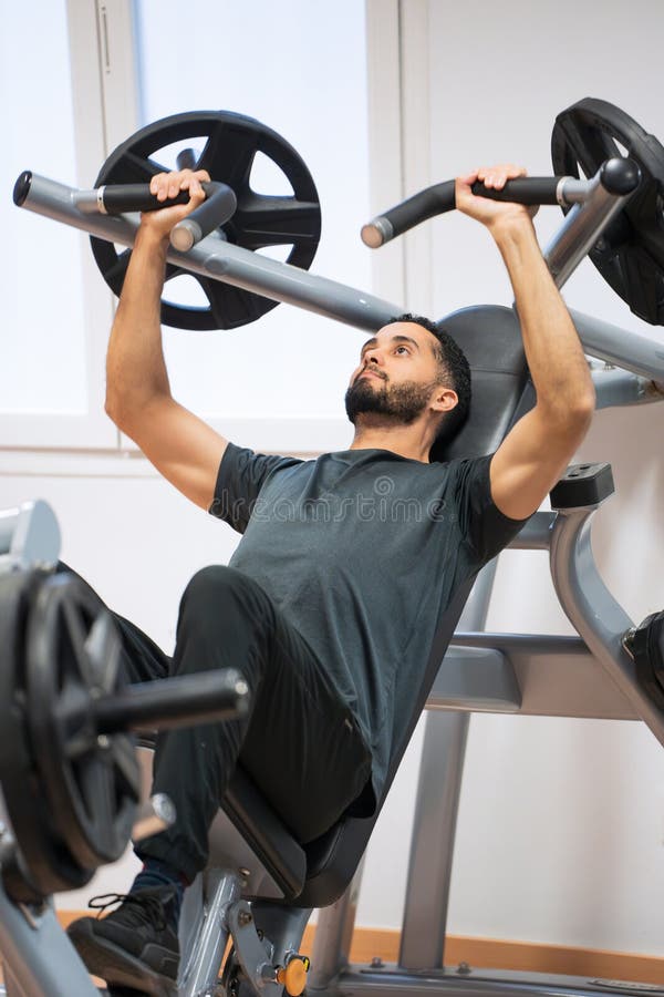 Man Using Chest Press at Gym in Focused Workout Session. Stock Photo ...