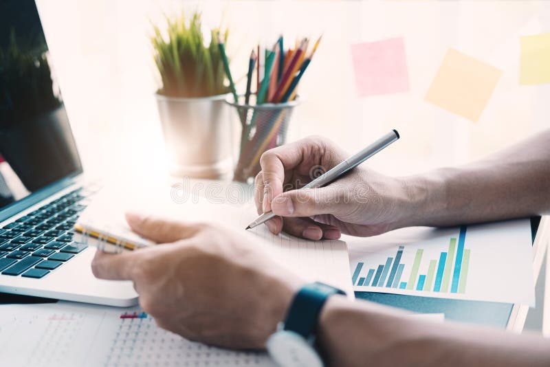 Man Using Computer and Calculator during Note Some Data on Notepad for ...