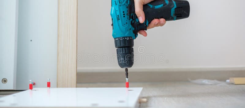 Man Using a Cordless Screwdriver Assembling Furniture at Home ...