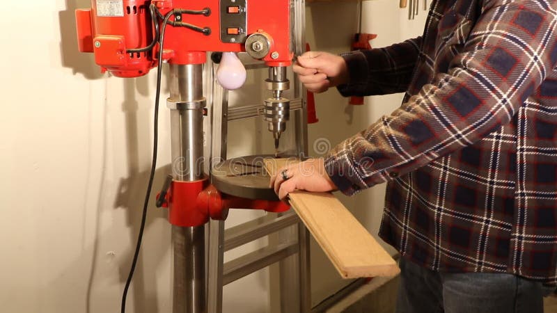 Man Using a Drill Press To Drill a Hole in a Piece of Wood Stock ...