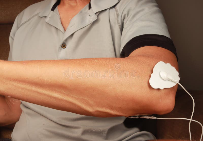 Man Using an Electro Therapy Massager or Tens Unit on His Elbow Stock ...