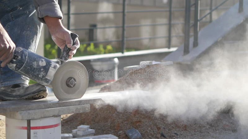 A Man is Using a Grinder To Cut a Piece of Concrete Stock Footage ...
