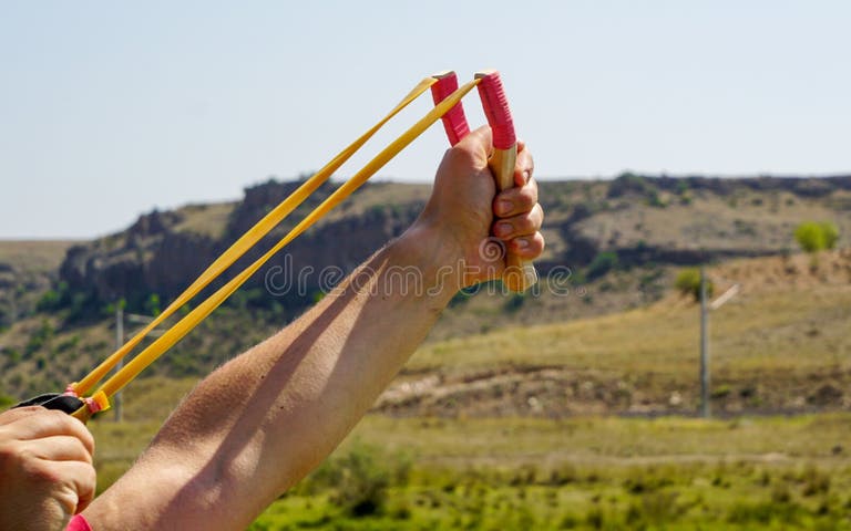 Man Using a Handmade Rubber Slingshot Against a Blurred Background ...