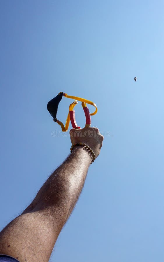Man Using a Handmade Rubber Slingshot Against a Blurred Background ...