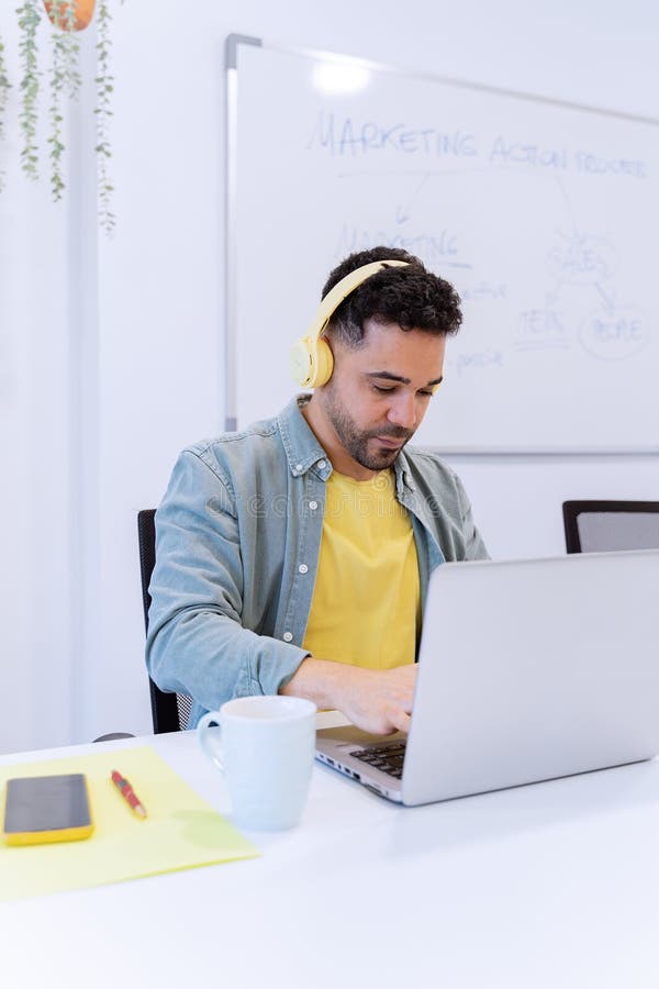 Man Using Headphones while Working with a Laptop in the Office. Stock ...