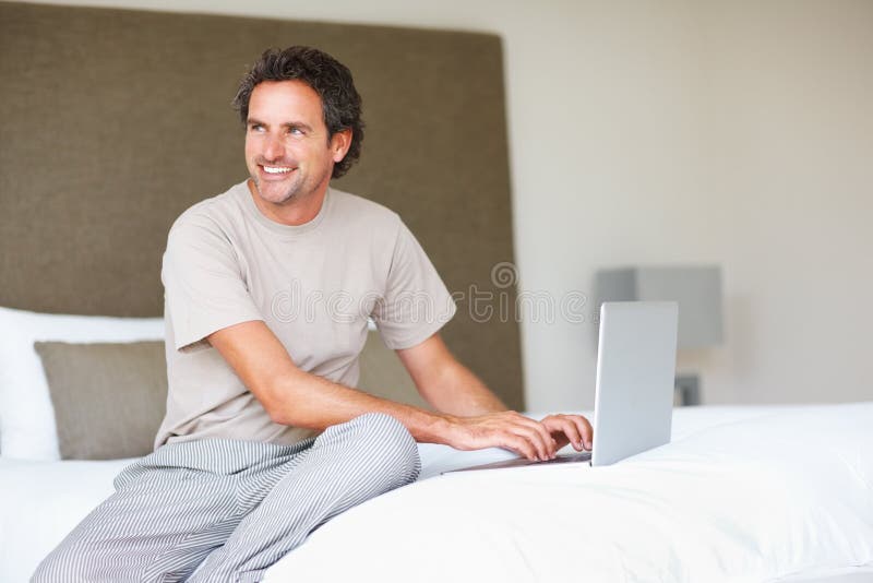 Man Using Laptop in Bed. Happy Mature Man Sitting on Bed and Working on ...