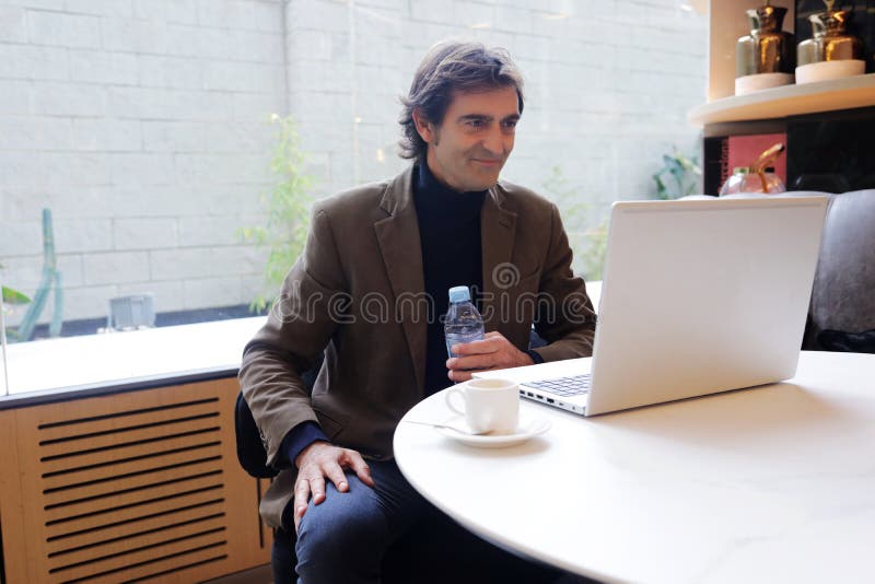 Man Using Laptop in a Cafe Bar while Holding a Water Bottle Stock Image ...