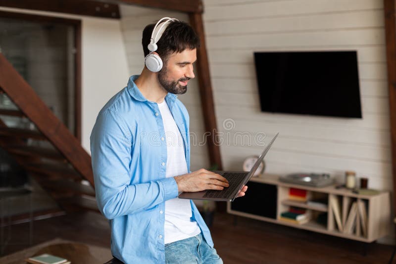Man Using Laptop Computer with Headphones at Home Interior Stock Image ...