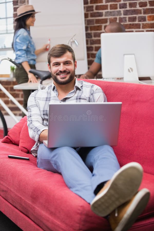 Man Using Laptop on Couch in Office Stock Photo - Image of sitting ...