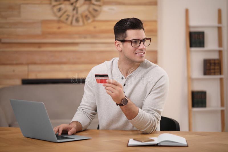 Man Using Laptop and Credit Card for Online Payment at Desk in Room ... Man Using Laptop and Credit Card for Online Payment at Desk in Room ...