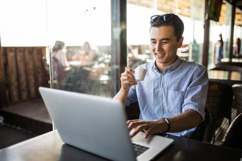 Man Using a Laptop and Drinking Coffee in a Coffee Shop. Freelance Work ...