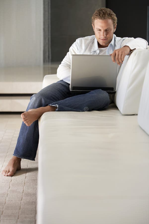 Man Using Laptop on Sofa stock image. Image of comfortable - 33840619