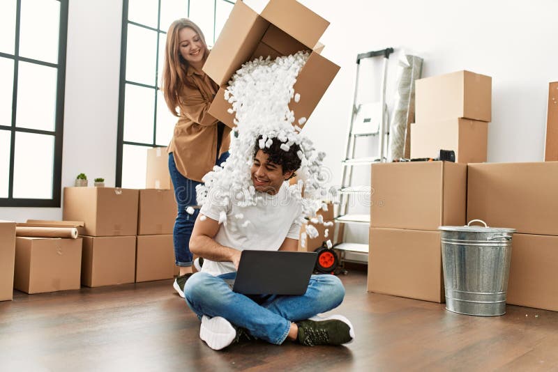 Man Using Laptop while Woman Throwing Foam Package at New Home Stock ...
