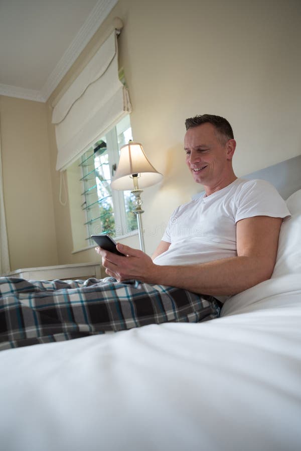 Man Using Mobile Phone on Bed in Bedroom Stock Image - Image of ...
