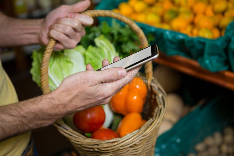 Man Using Mobile Phone while Buying Vegetables Stock Photo - Image of ...