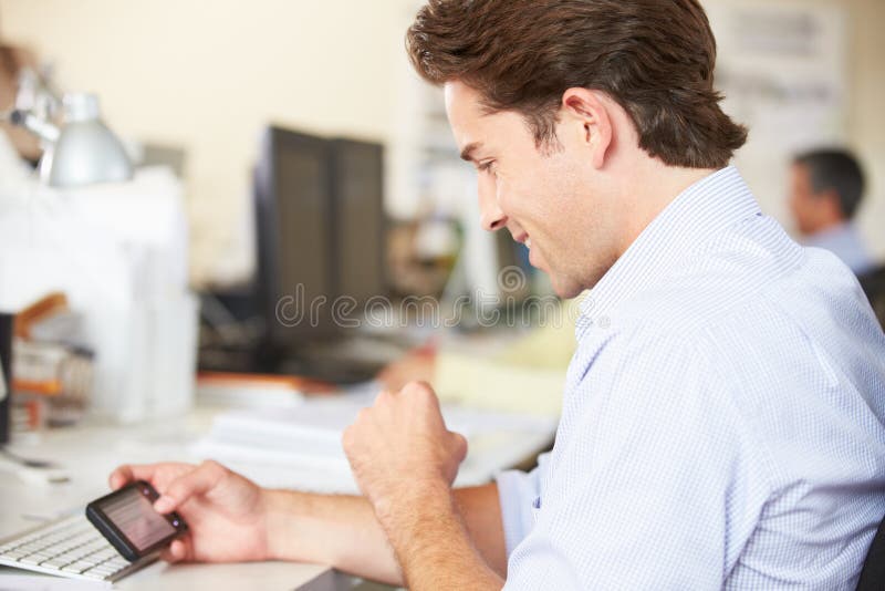 Man Using Mobile Phone at Desk in Busy Creative Office Stock Photo ...