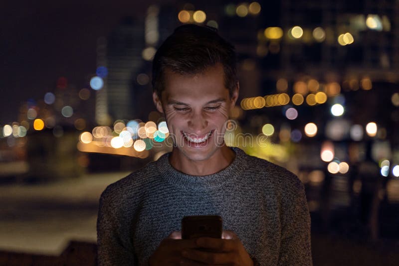 Young Man Using Her Smartphone during the Night. City Light As ...