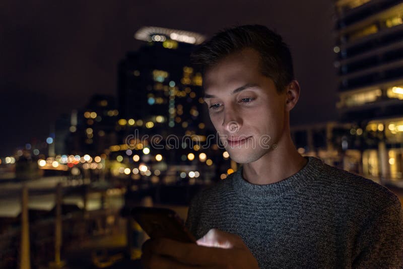 Young Man Using Her Smartphone during the Night. City Light As ...