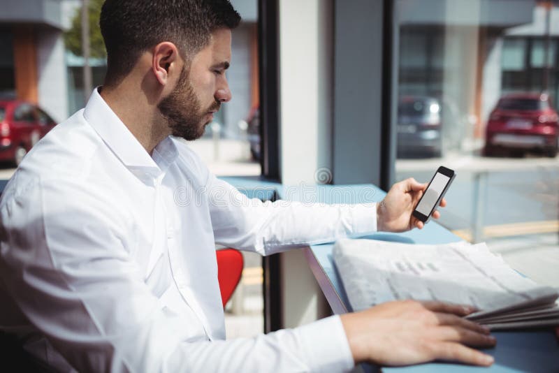 Man Using Mobile Phone while Reading Newspaper Stock Image - Image of ...