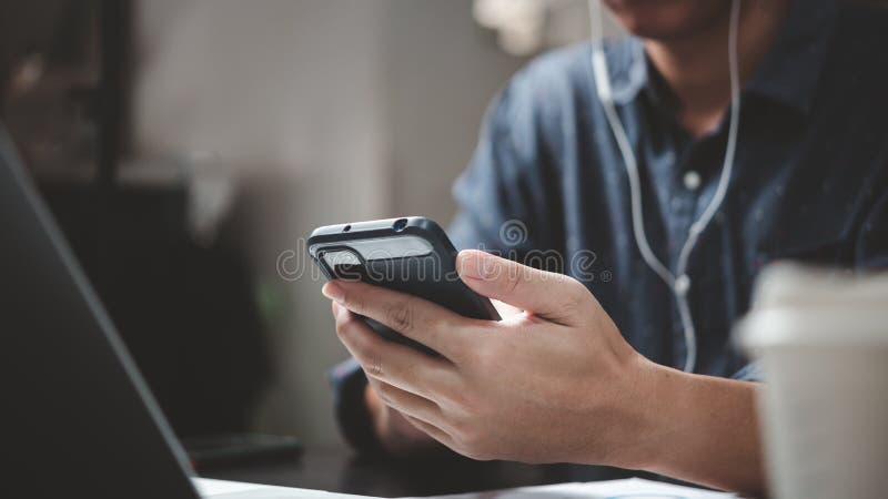 Man Using Mobile Phone Working on Laptop Computer on Desk at Office ...