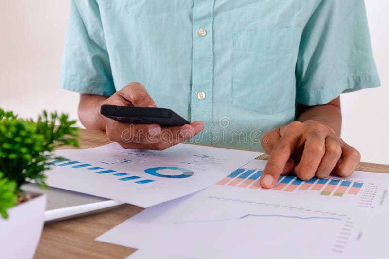 Man Using a Mobile Phone at Workplace with Laptop and Documents on the ...
