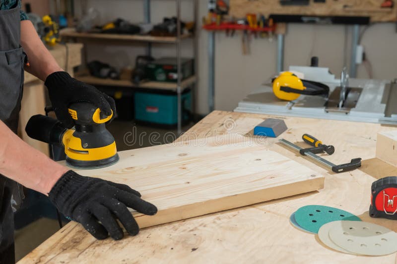 A Man Using an Orbital Wood Sander in a Workshop. Close-up of a ...