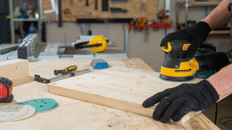A Man Using an Orbital Wood Sander in a Workshop. Close-up of a ...