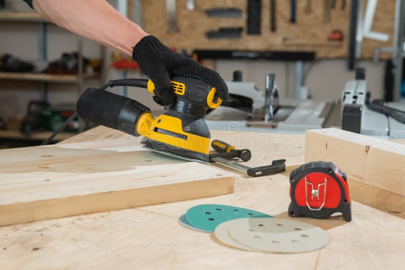 A Man Using an Orbital Wood Sander in a Workshop. Close-up of a ...