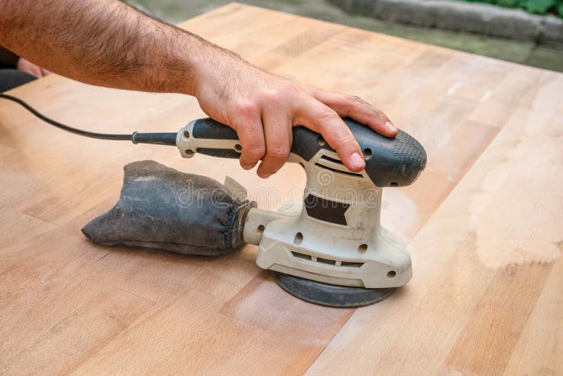A Man Using an Orbital Wood Sander in a Workshop. Close-up of a ...