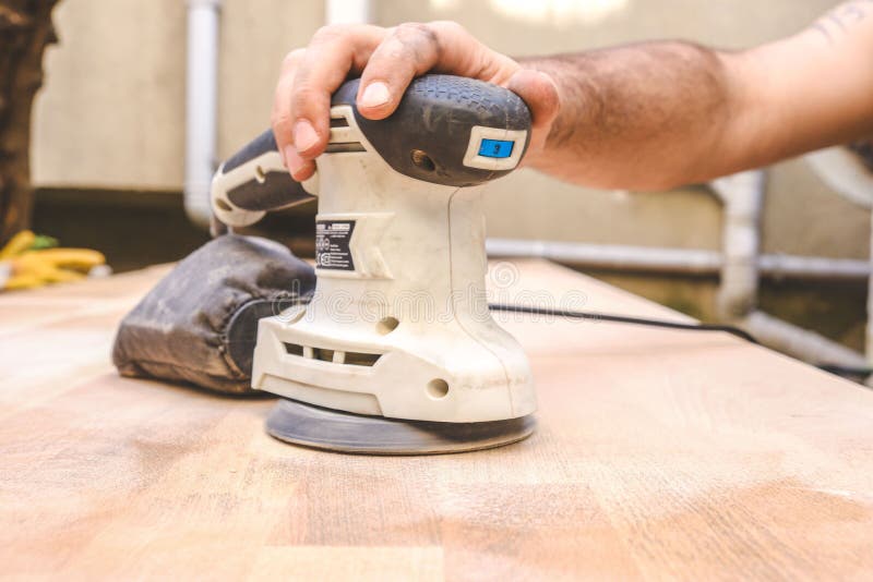 A Man Using an Orbital Wood Sander in a Workshop. Close-up of a ...