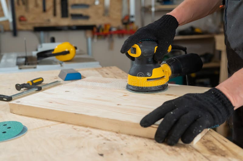 A Man Using an Orbital Wood Sander in a Workshop. Close-up of a ...