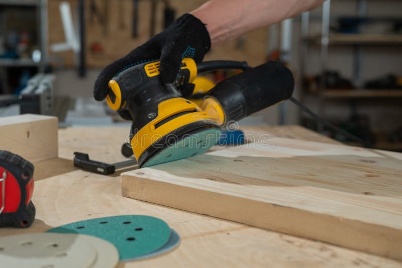 A Man Using an Orbital Wood Sander in a Workshop. Close-up of a ...
