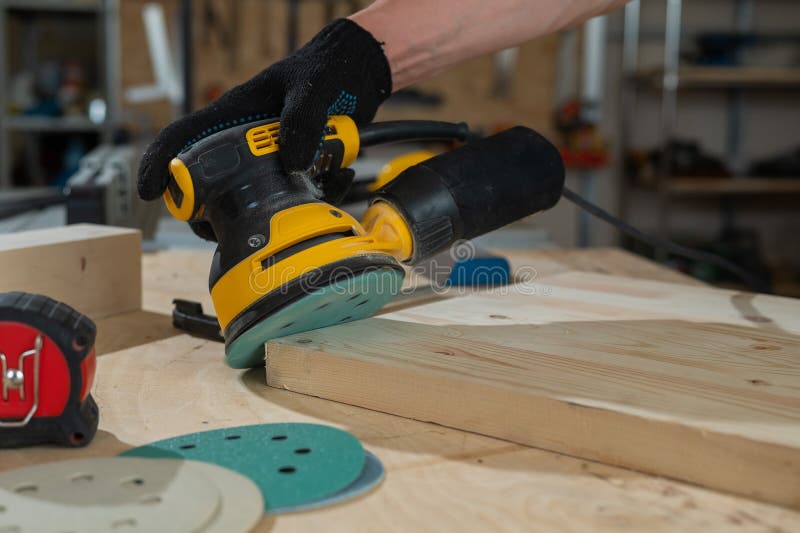 A Man Using an Orbital Wood Sander in a Workshop. Close-up of a ...