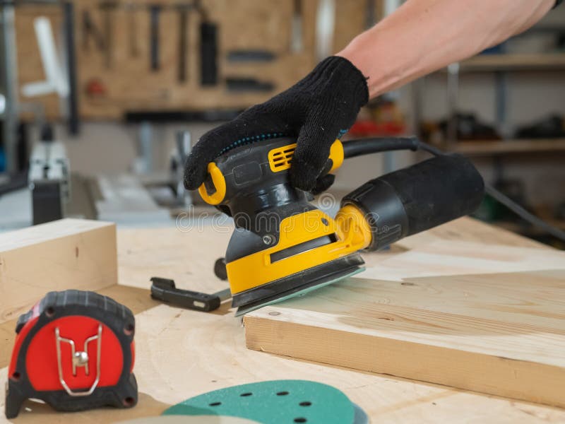A Man Using an Orbital Wood Sander in a Workshop. Close-up of a ...