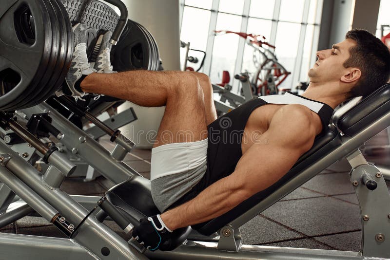 Man Using a Press Machine in a Fitness Club. Strong Man Doing an ...